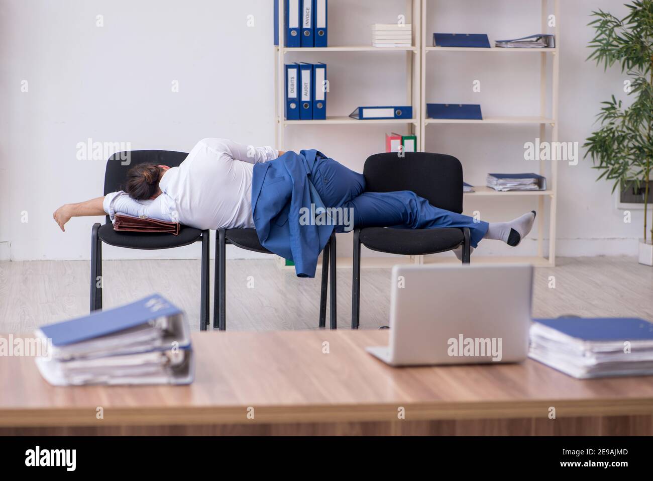 Young employee sleeping in the office on chairs Stock Photo - Alamy