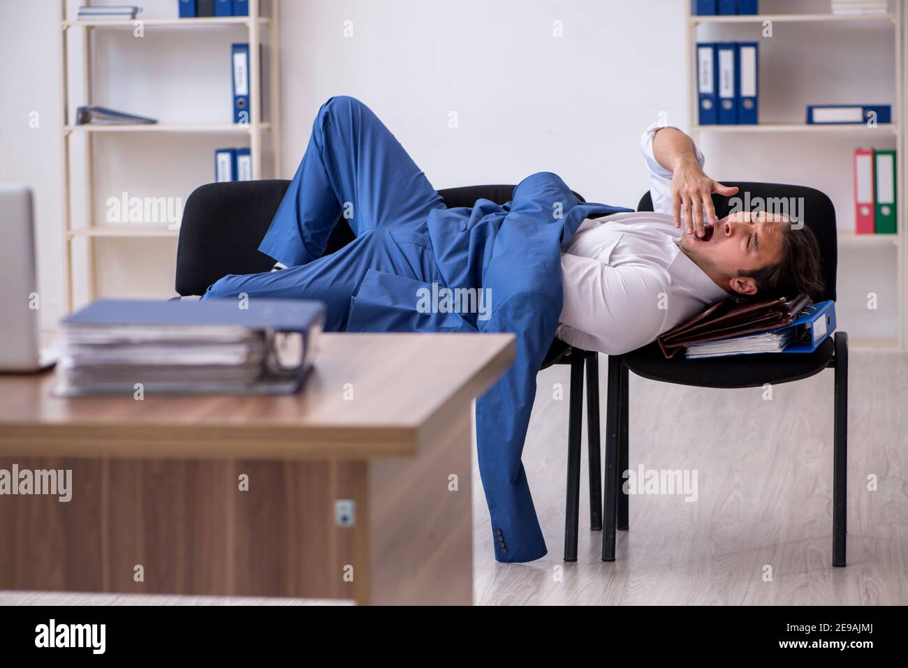 Young employee sleeping in the office on chairs Stock Photo - Alamy