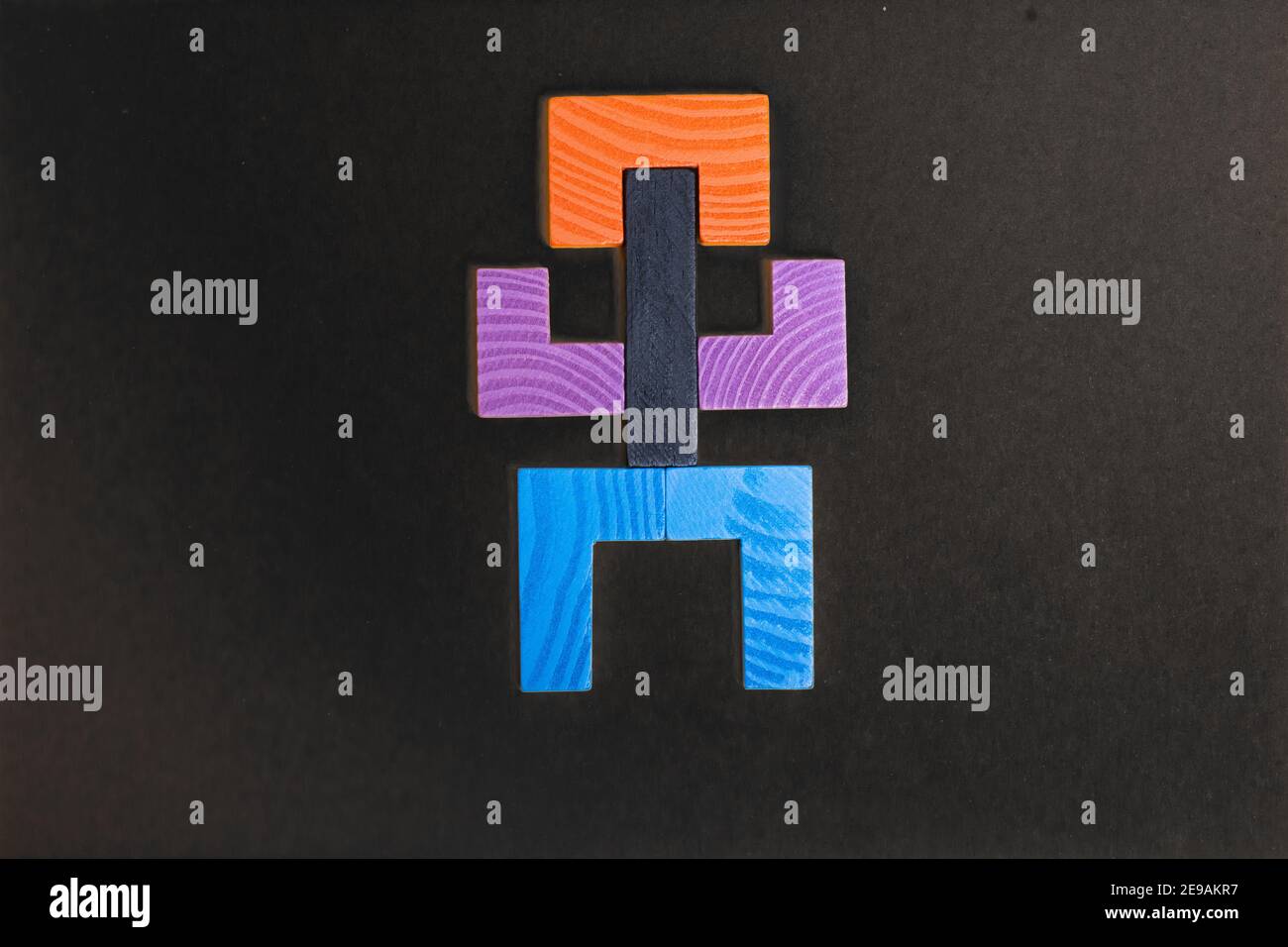 Top view of a colorful human figure made from wood on a black surface ...