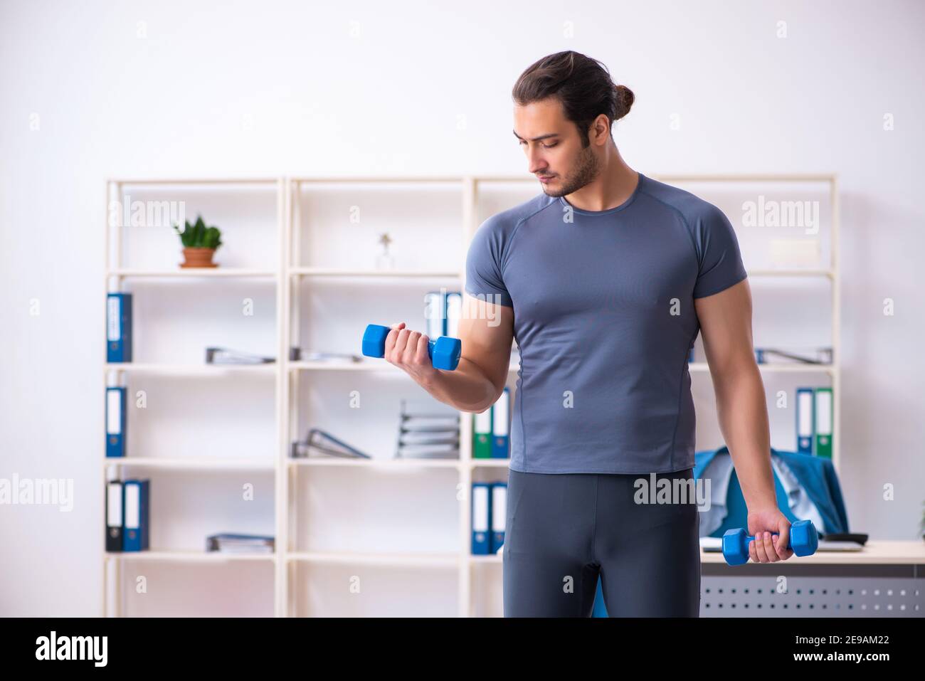 Young male employee doing sport exercises in the office Stock Photo - Alamy