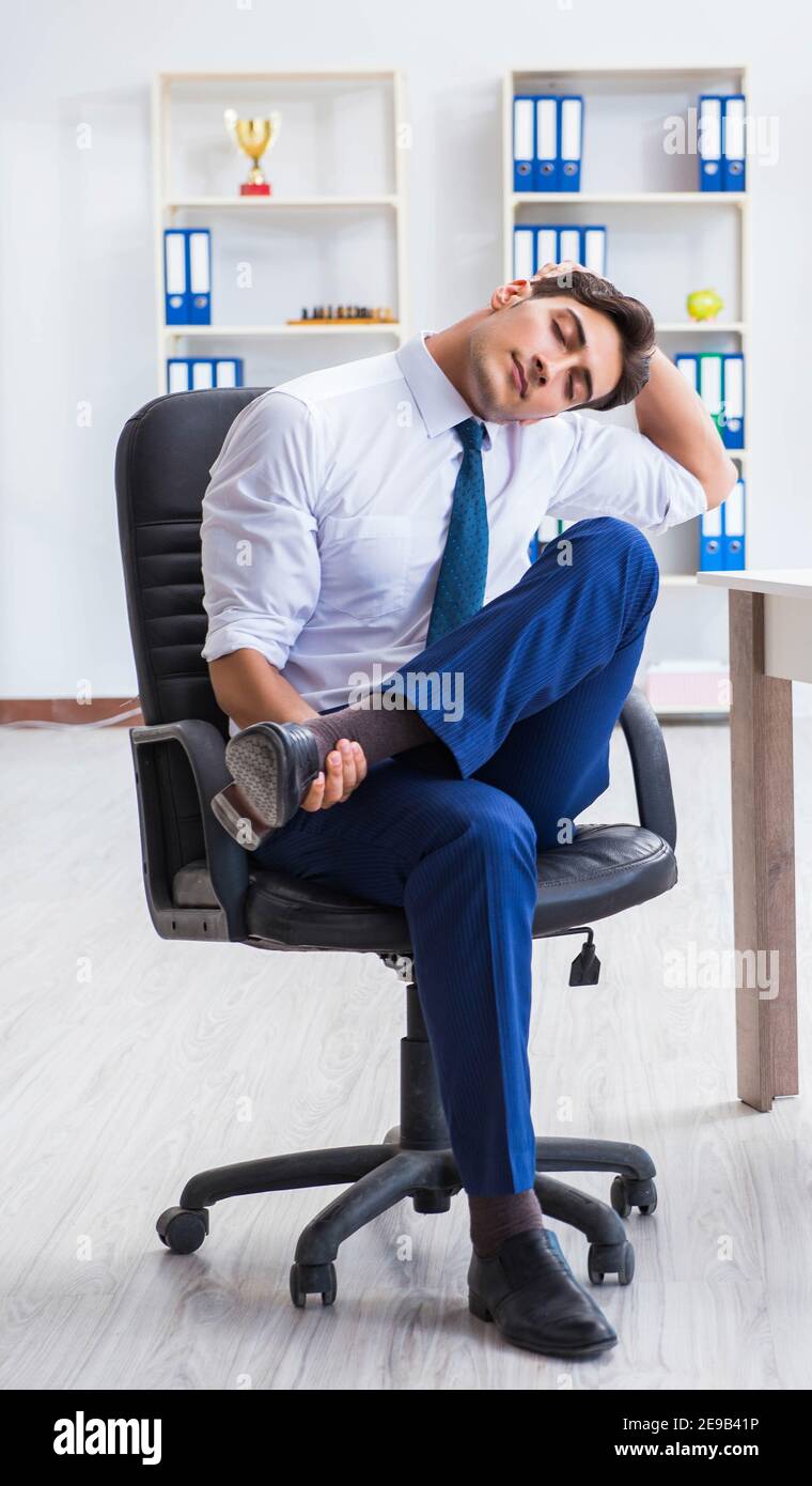 The young businessman doing sports stretching at workplace Stock Photo ...