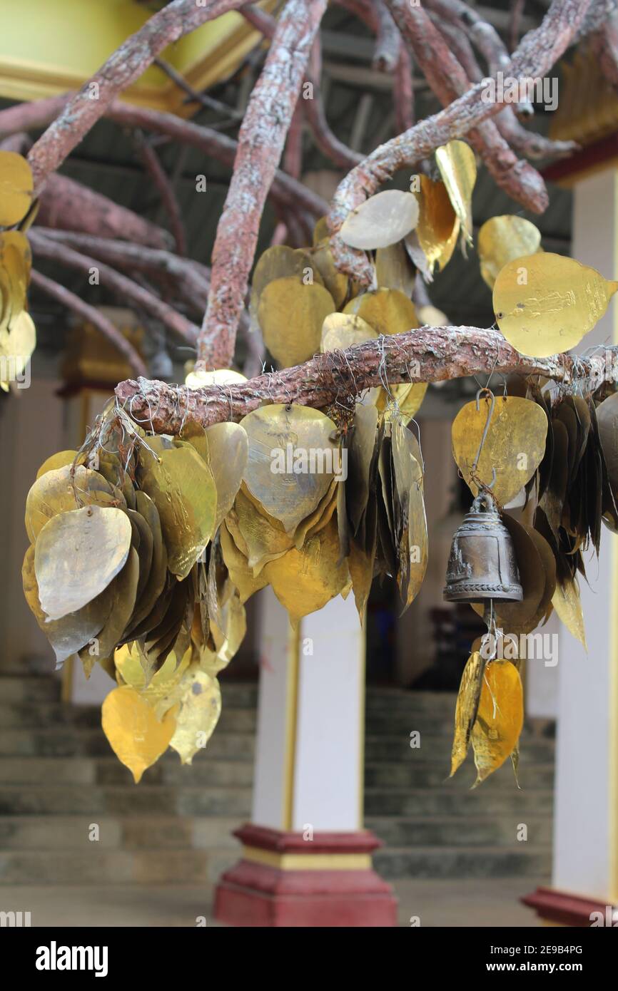 Vertical shot of metal yellow leaves and a tiny bell hanging from a ...