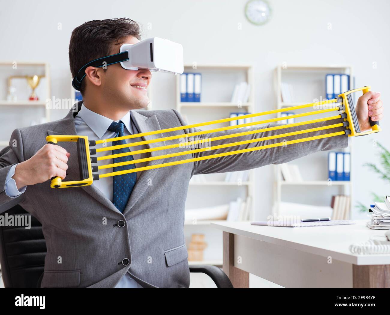 The businessman exercising with elastic expander wearing vr glasses ...