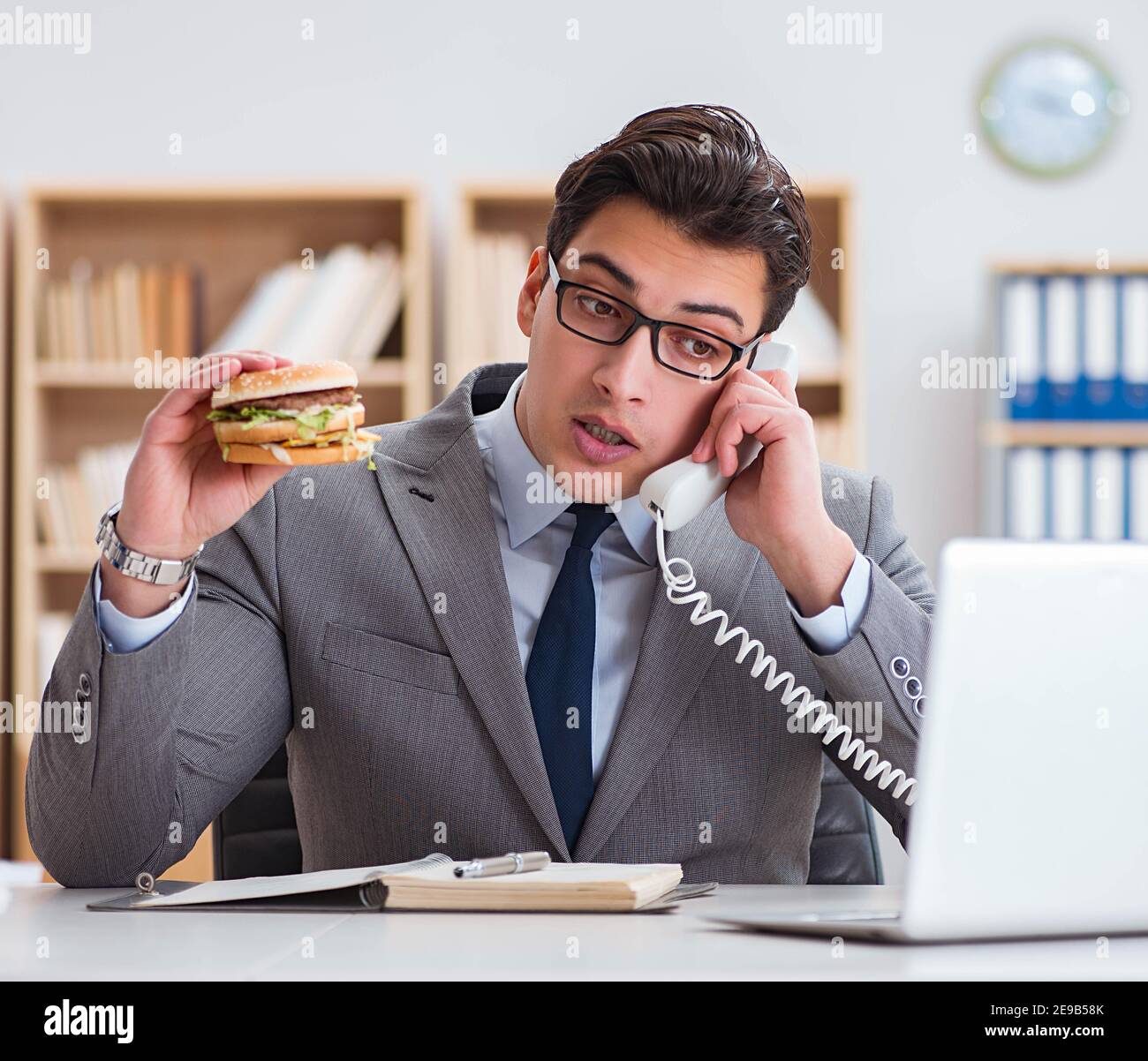 The hungry funny businessman eating junk food sandwich Stock Photo - Alamy