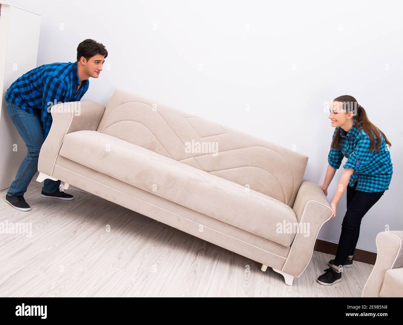 The wife and husband moving sofa couch Stock Photo - Alamy