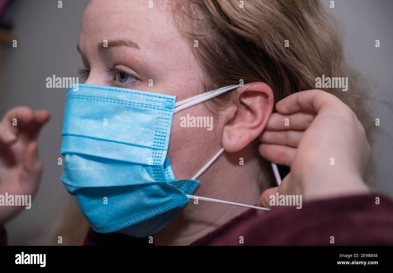 White woman wearing double face masks for covid prevention, side shot ...