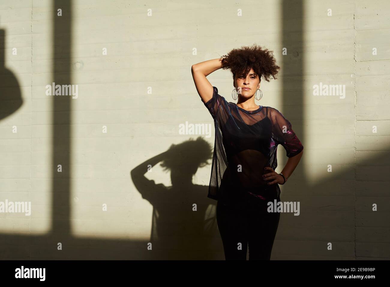 Portrait of a young woman with afro hair, her shadow is projected ...