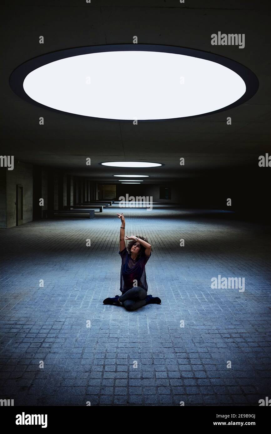 Woman sitting in a building under the light of a skylight Stock Photo ...