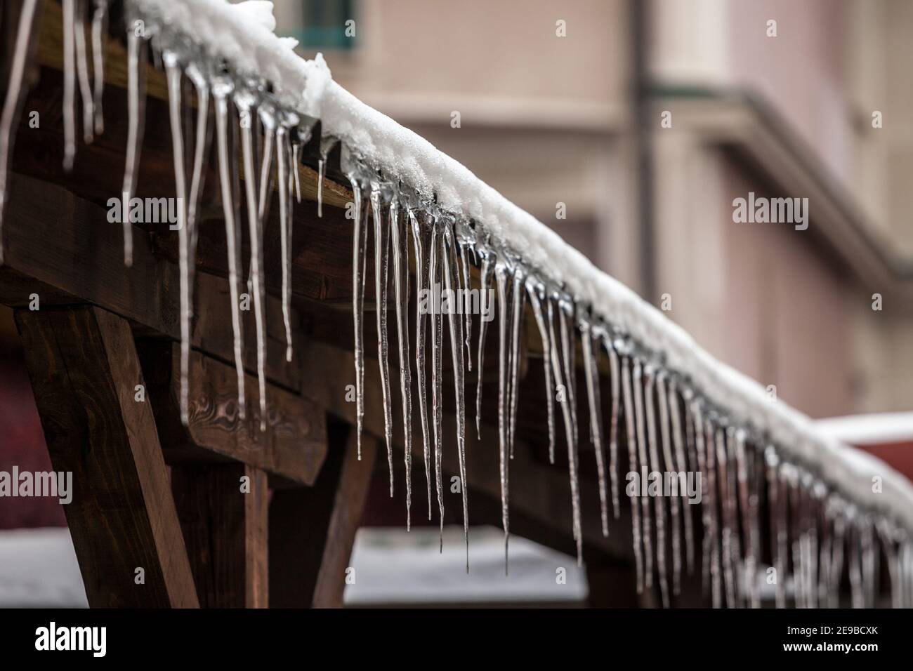 Icicles forming ice stalactites falling fron the edge of the eaves of ...