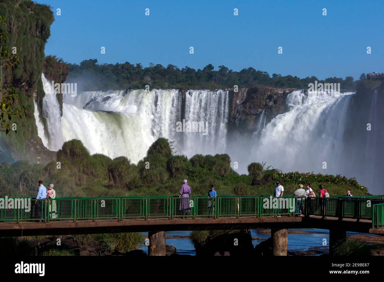 Tourists on a raised walkway admire a section of Iguazu Falls in Brazil ...