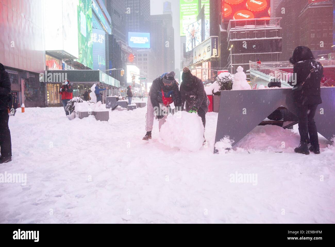 Girls rolling a large ball of snow to build a Snowman in Times Square ...