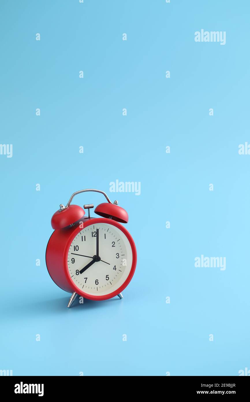 Red retro alarm clock isolated on a blue background Stock Photo - Alamy