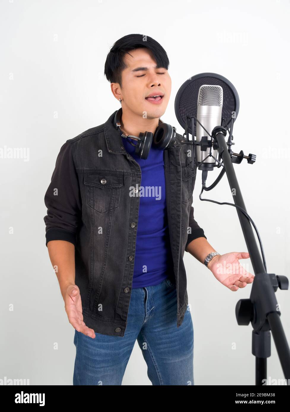 Young asian man with headphones singing with microphone. Portrait on ...