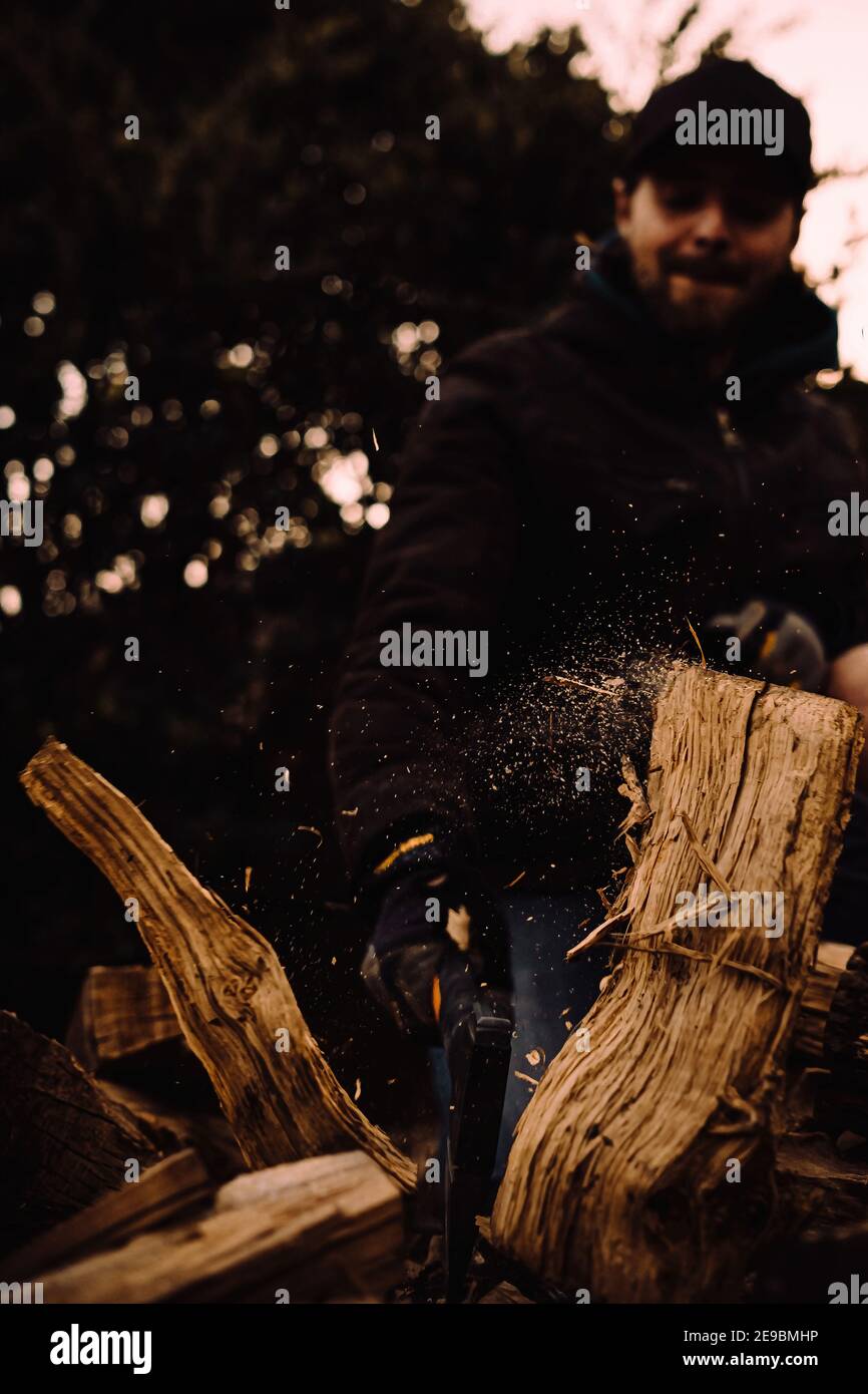 Chopping logs for firewood in action and close up with particles flying ...