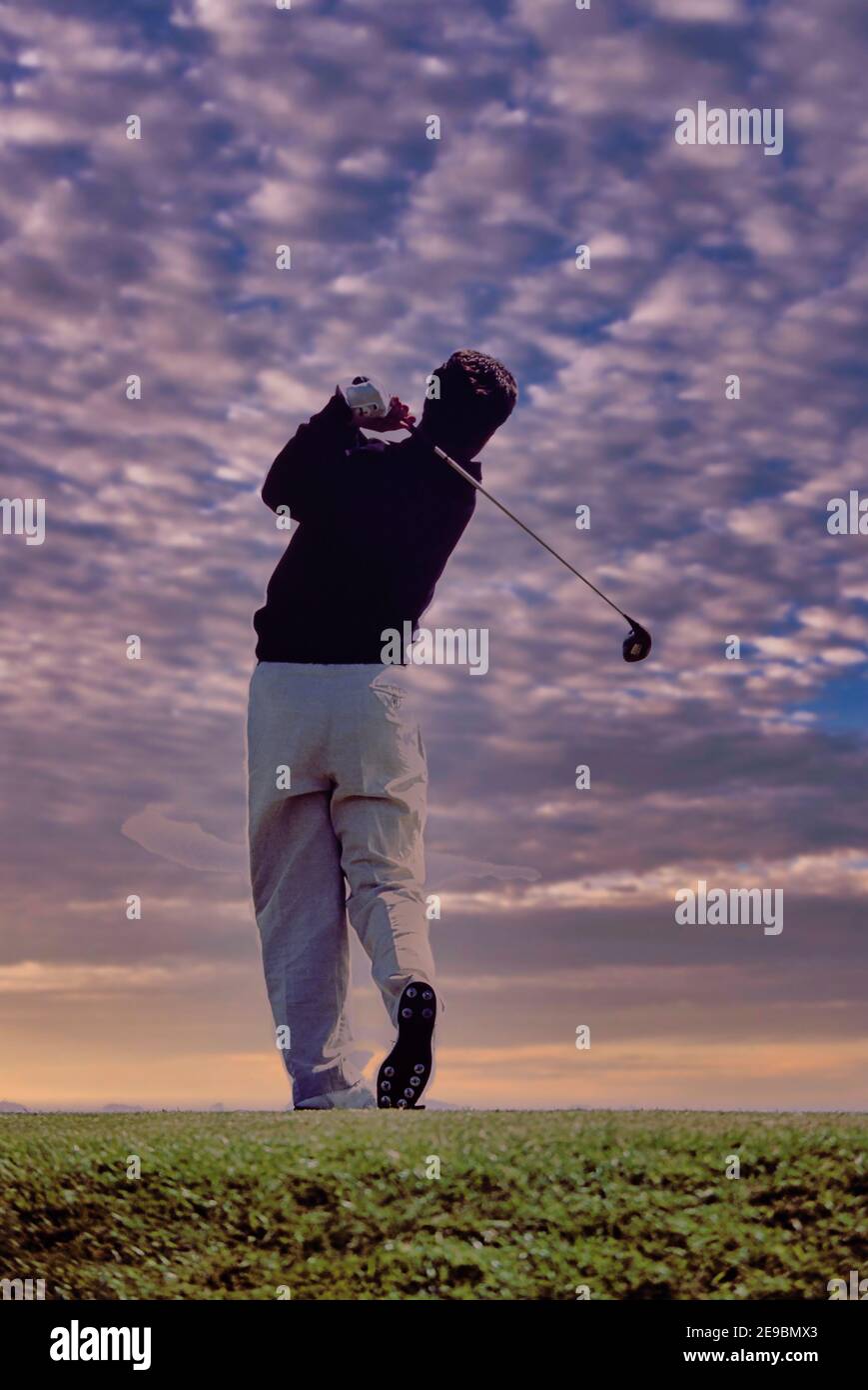 Golfer standing in follow through position after driving off - rear ...