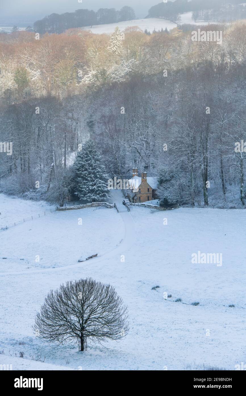 Cotswold cottage in the snow on the edge of a woodland. Lower Coscombe ...