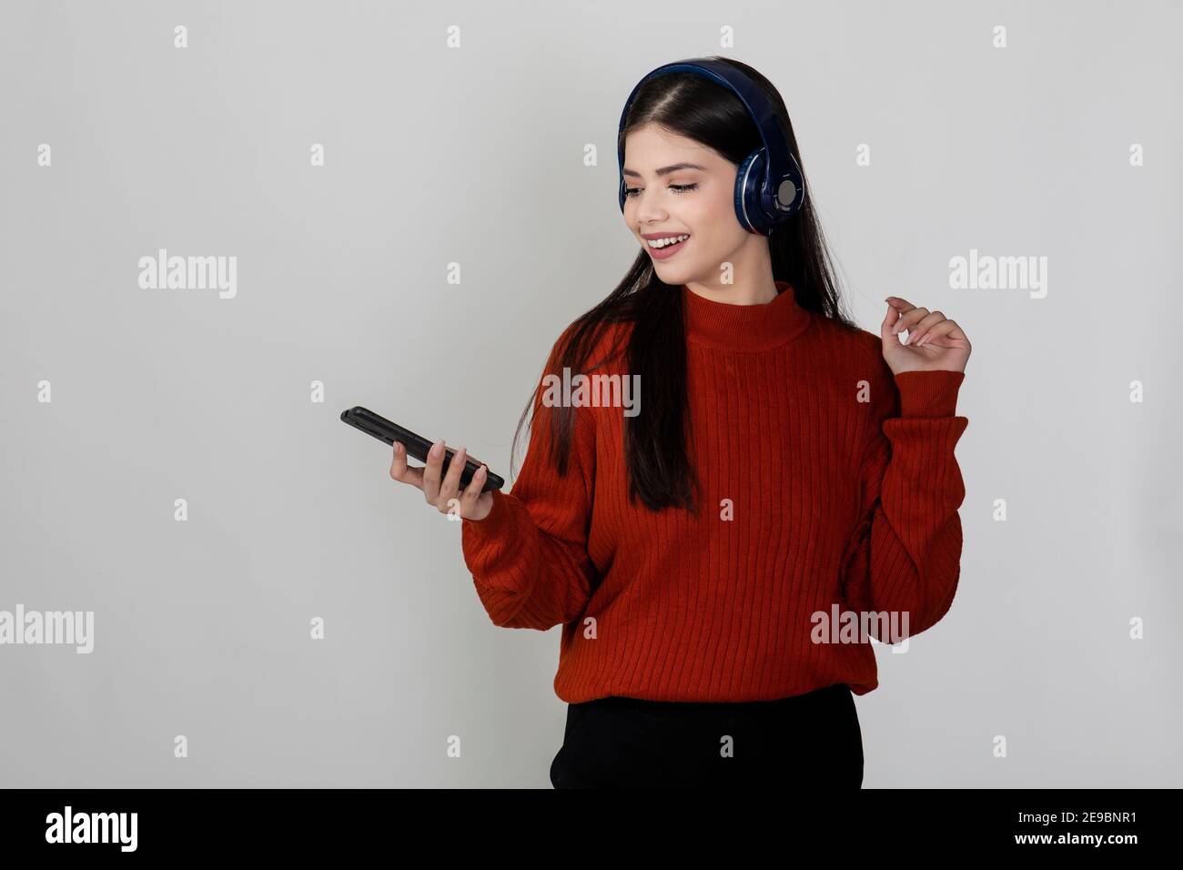 Pretty excited young girl wearing headphone and listening to music or ...