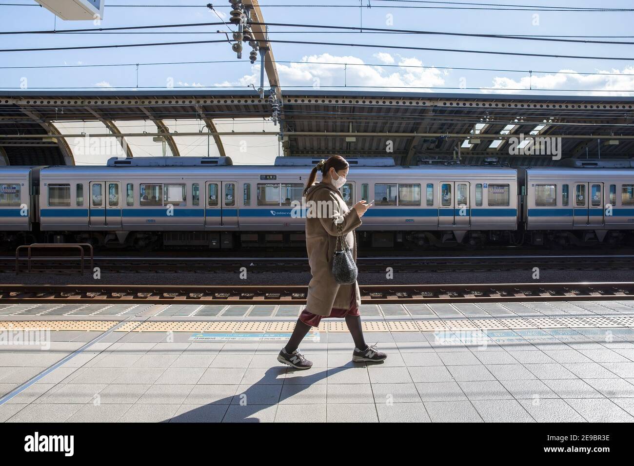 A woman wearing a mask walks on the platform at the Gotokuji Station ...