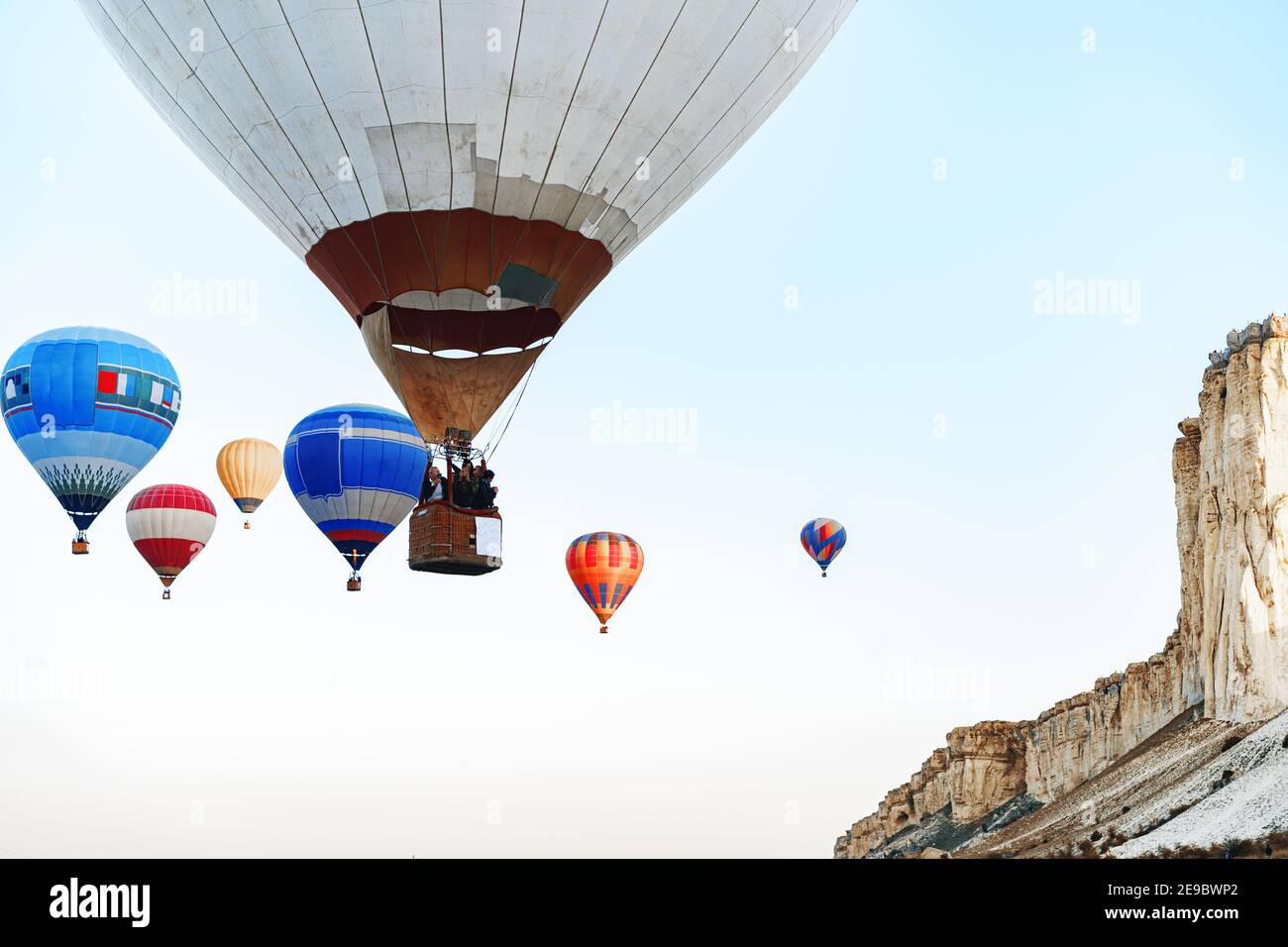 Colorful air balloons flying in clear sky near huge white mountain ...