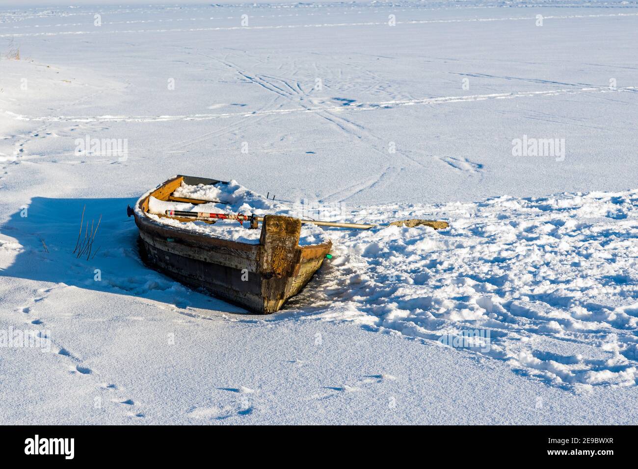 Wooden old boat in a frozen river or lake in a evening beautiful winter ...