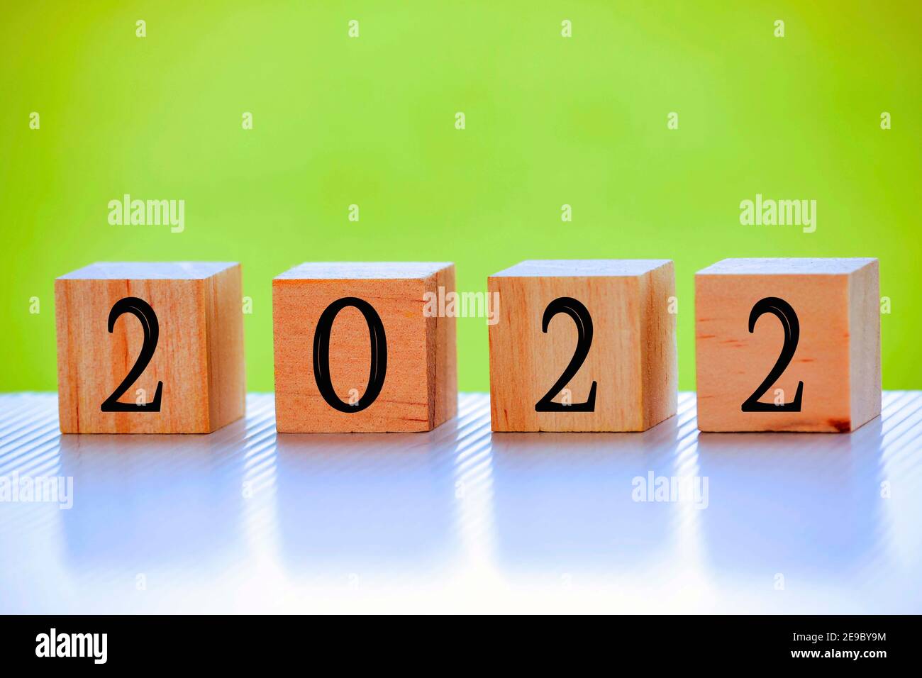 2022 number on wooden block with green background Stock Photo - Alamy