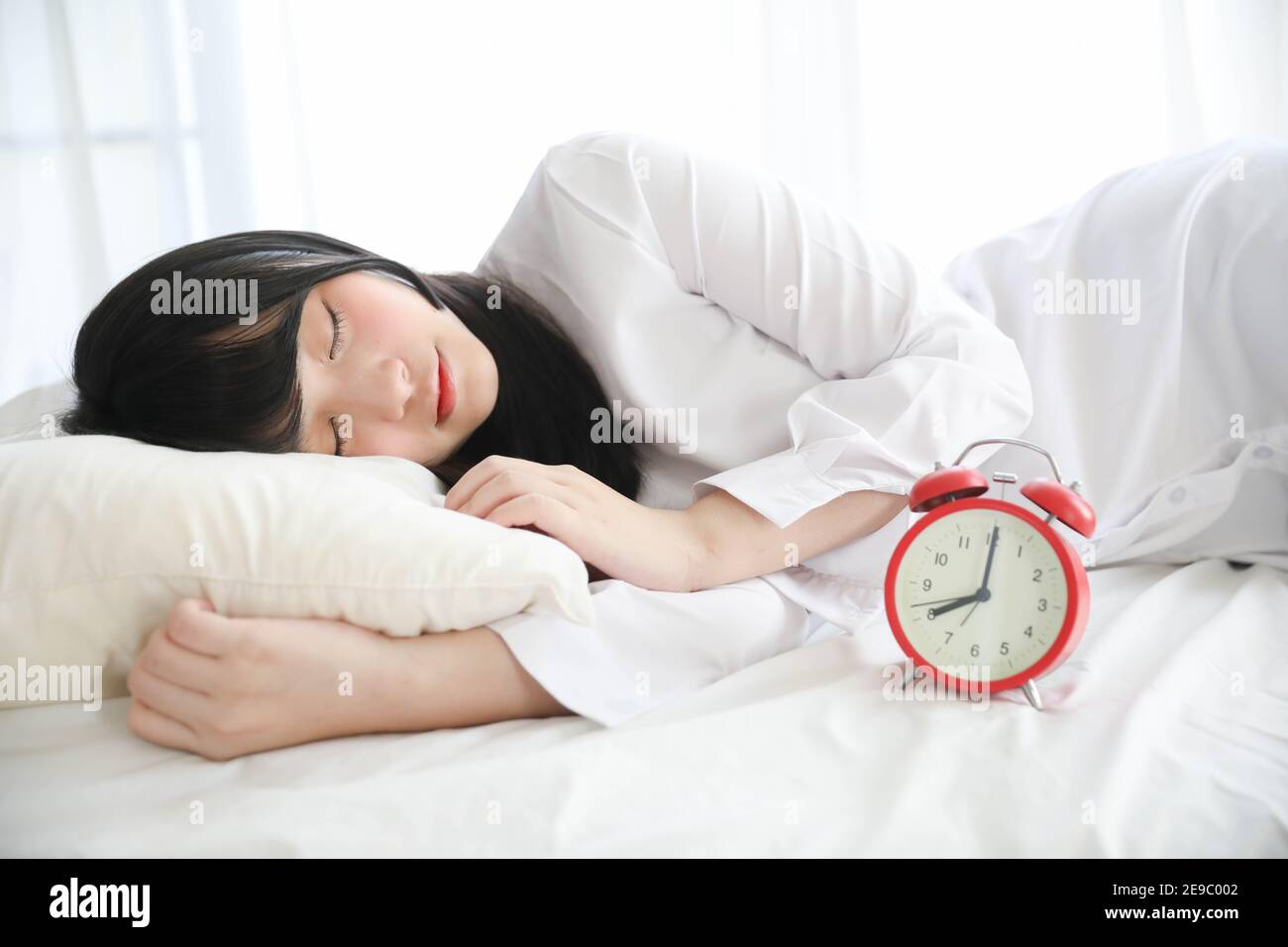 girl sleeping with clock at white bedroom Stock Photo - Alamy