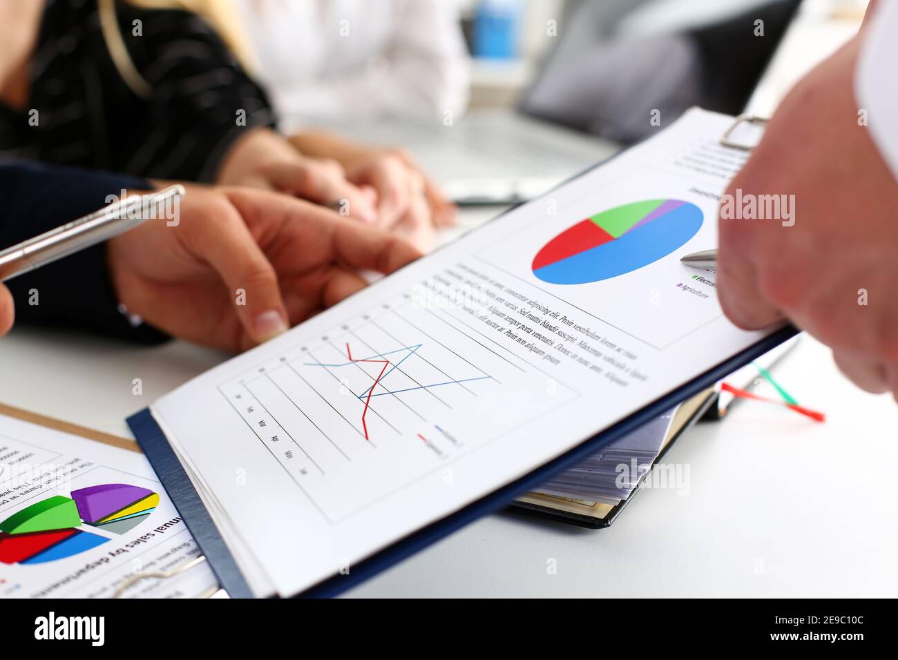 Group of people deliberate on problem with clipboard Stock Photo - Alamy