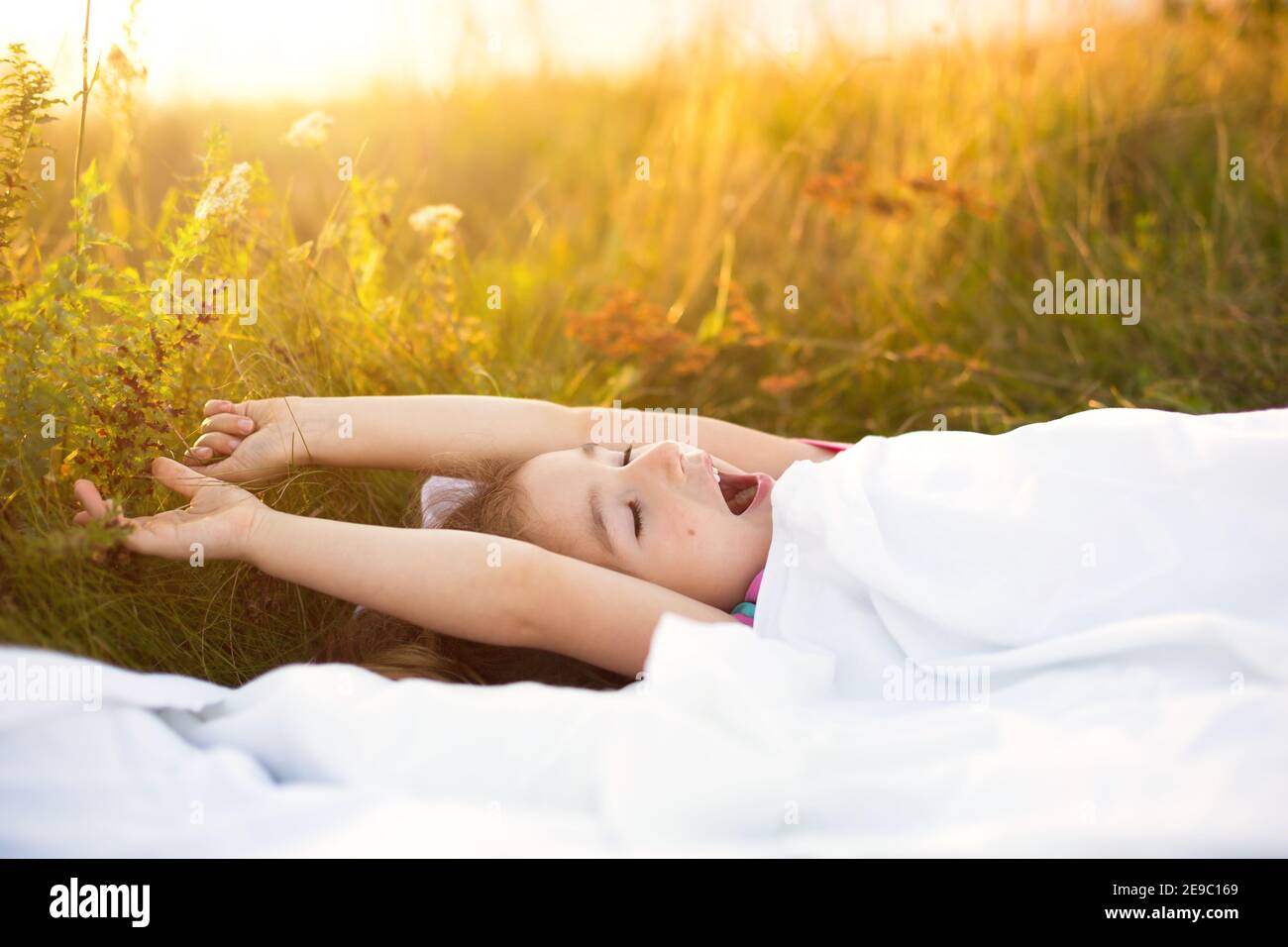 Girl sleeps on bed in grass, Sweet stretches and yawns sleepily, good ...