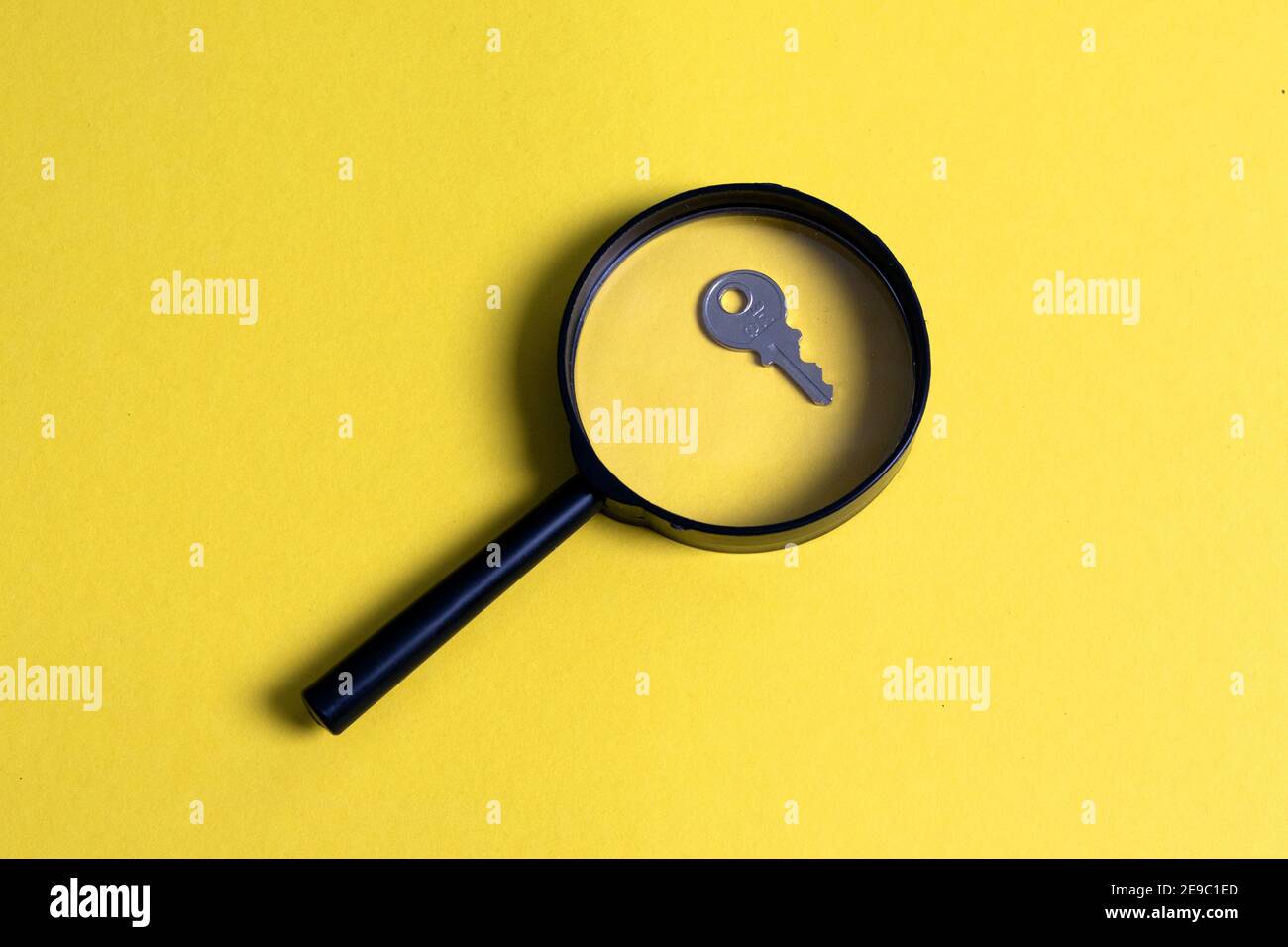 Magnifying glass with key on yellow background. Concept image of ...