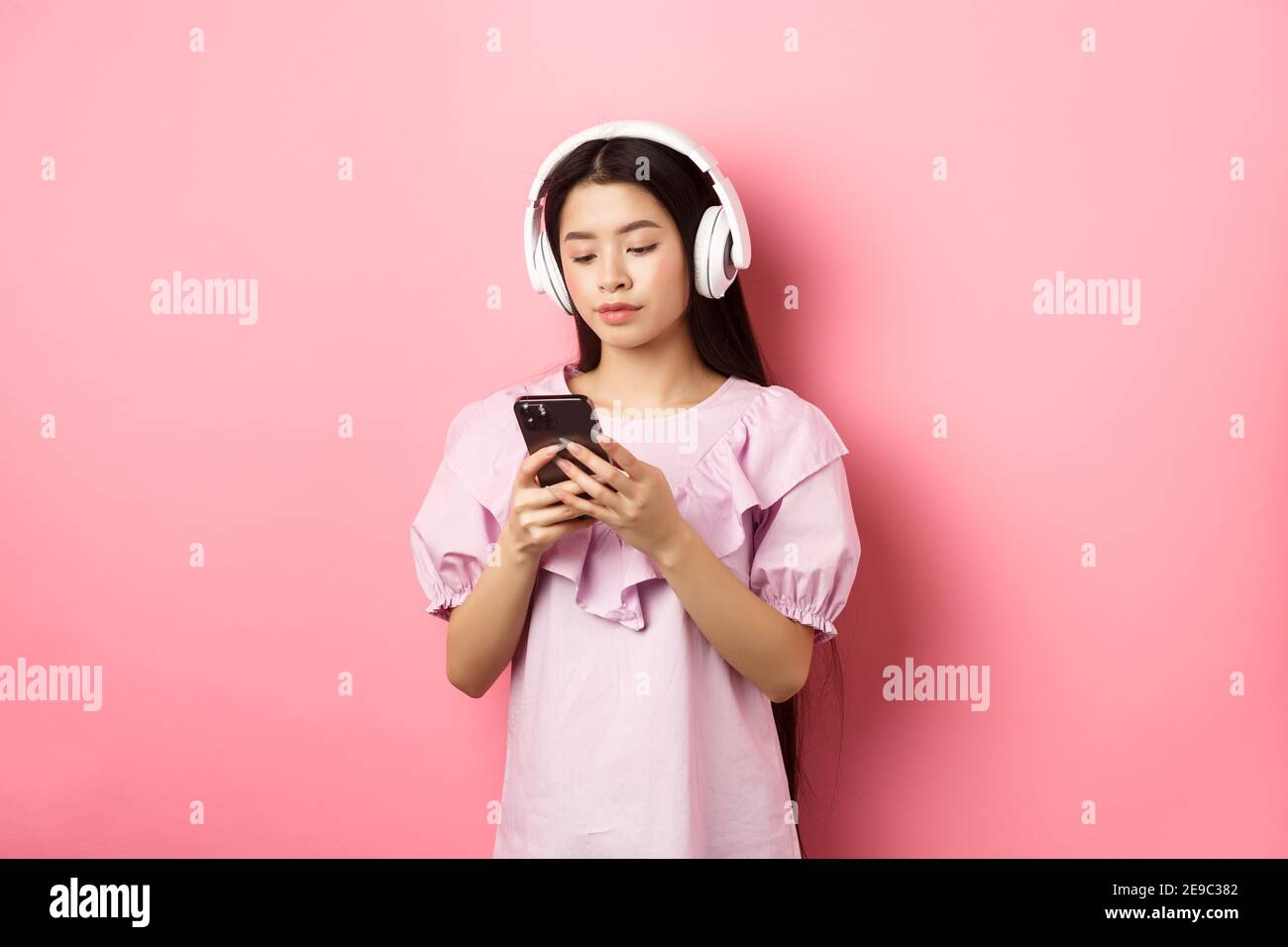 Young girl listening music in headphones and chatting on mobile phone ...