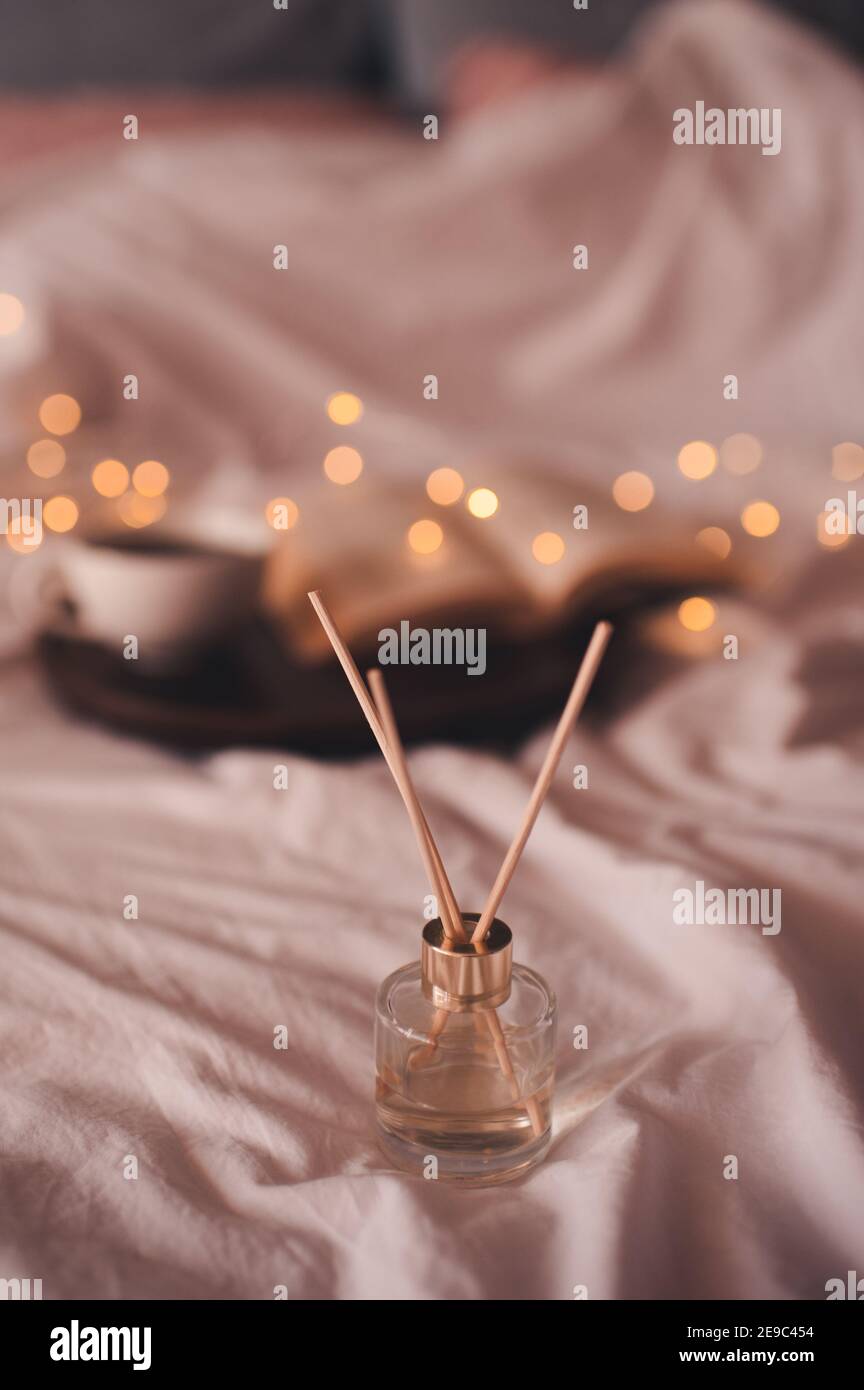 Liquid home perfume in glass bottle with sticks over glowing lights in ...