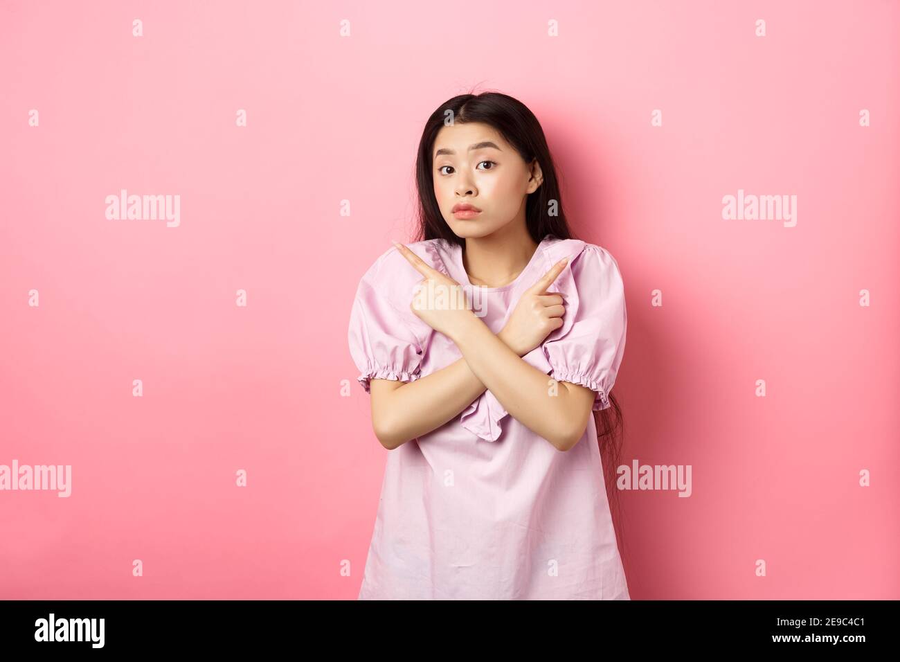 Clueless cute asian girl pointing sideways and look confused, cant make ...