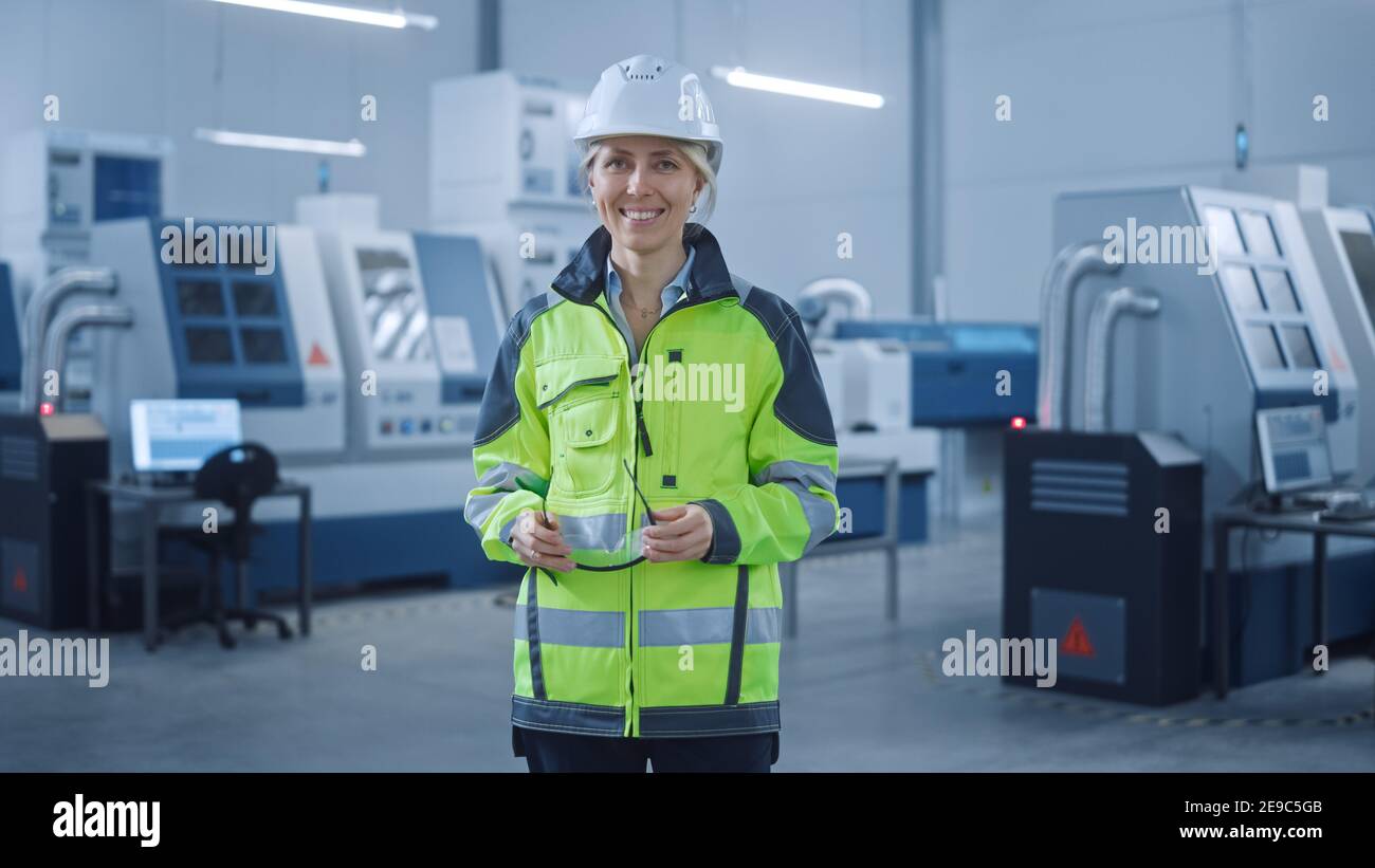 Beautiful Smiling Female Engineer Wearing Safety Vest and Hardhat Holds ...