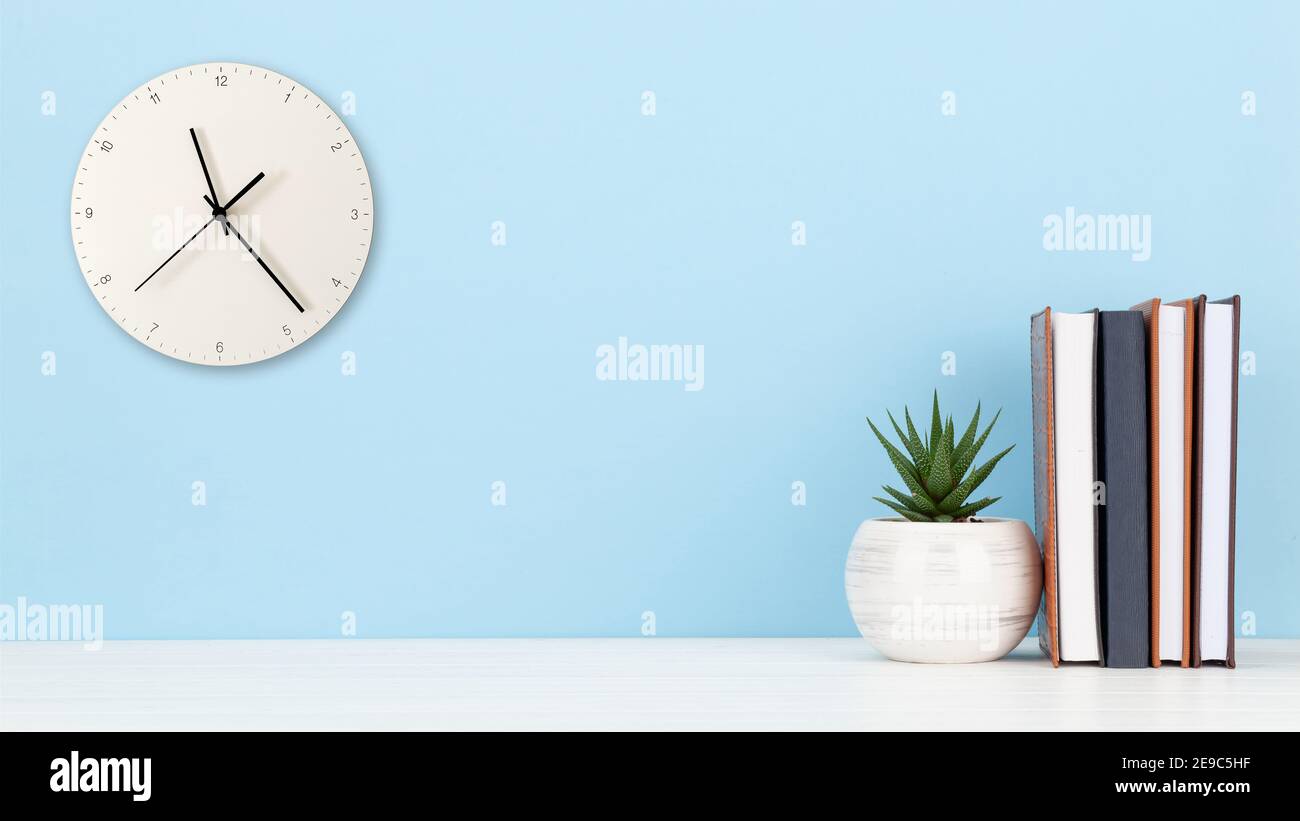 Office desk with wall clock, potted plant and notepads. Remote office ...