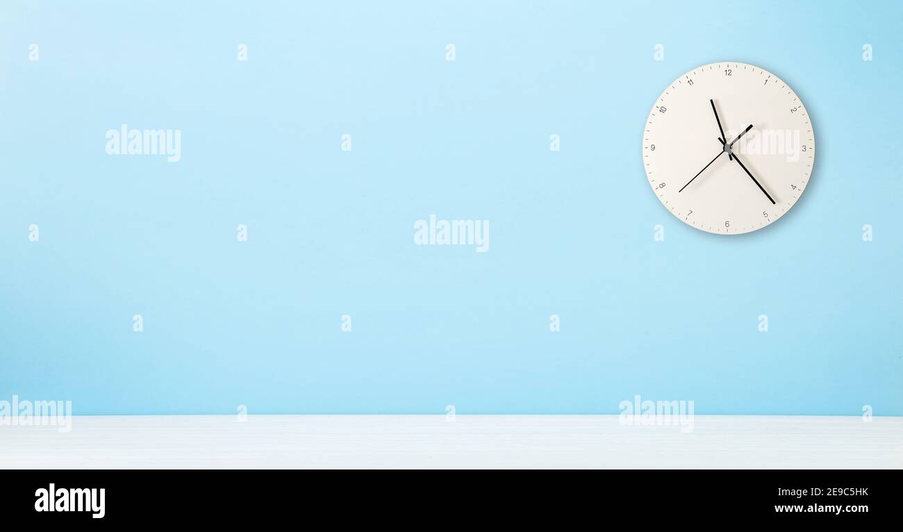 Office desk with wall clock on blue wall. Remote office and work from ...