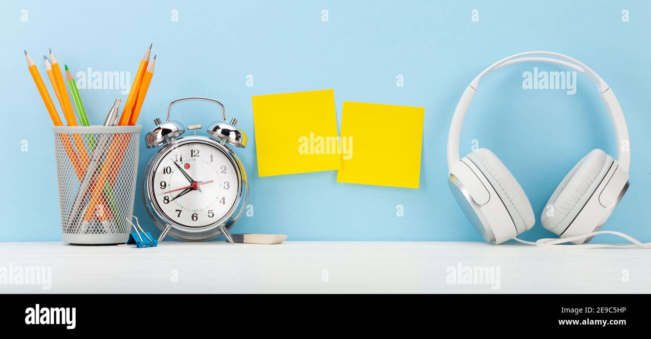 Office desk with alarm clock, supplies, stickers and headphones. Remote ...