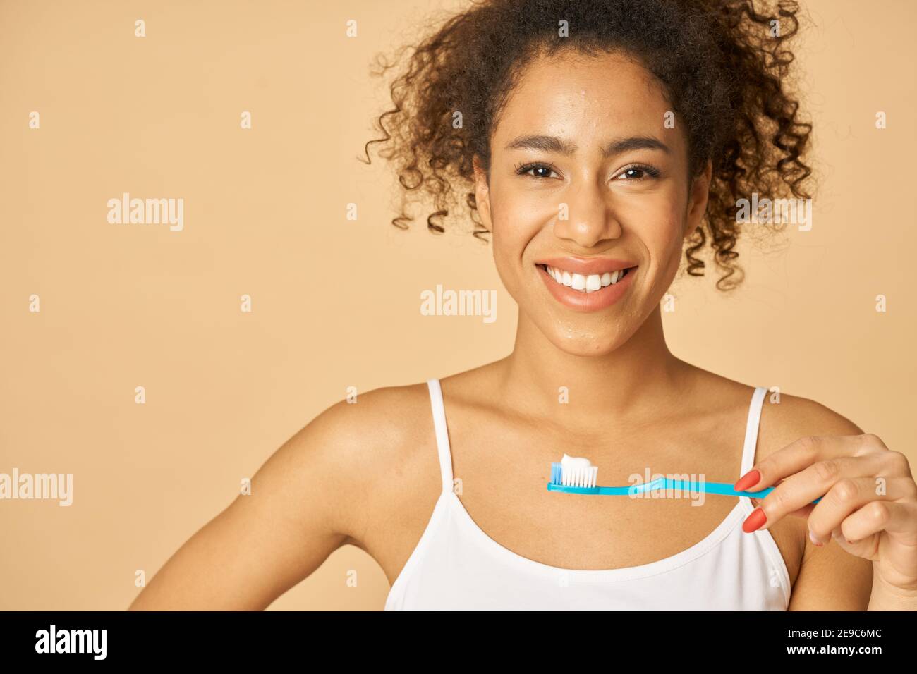 Portrait of cheerful young mixed race woman brushing teeth in the ...