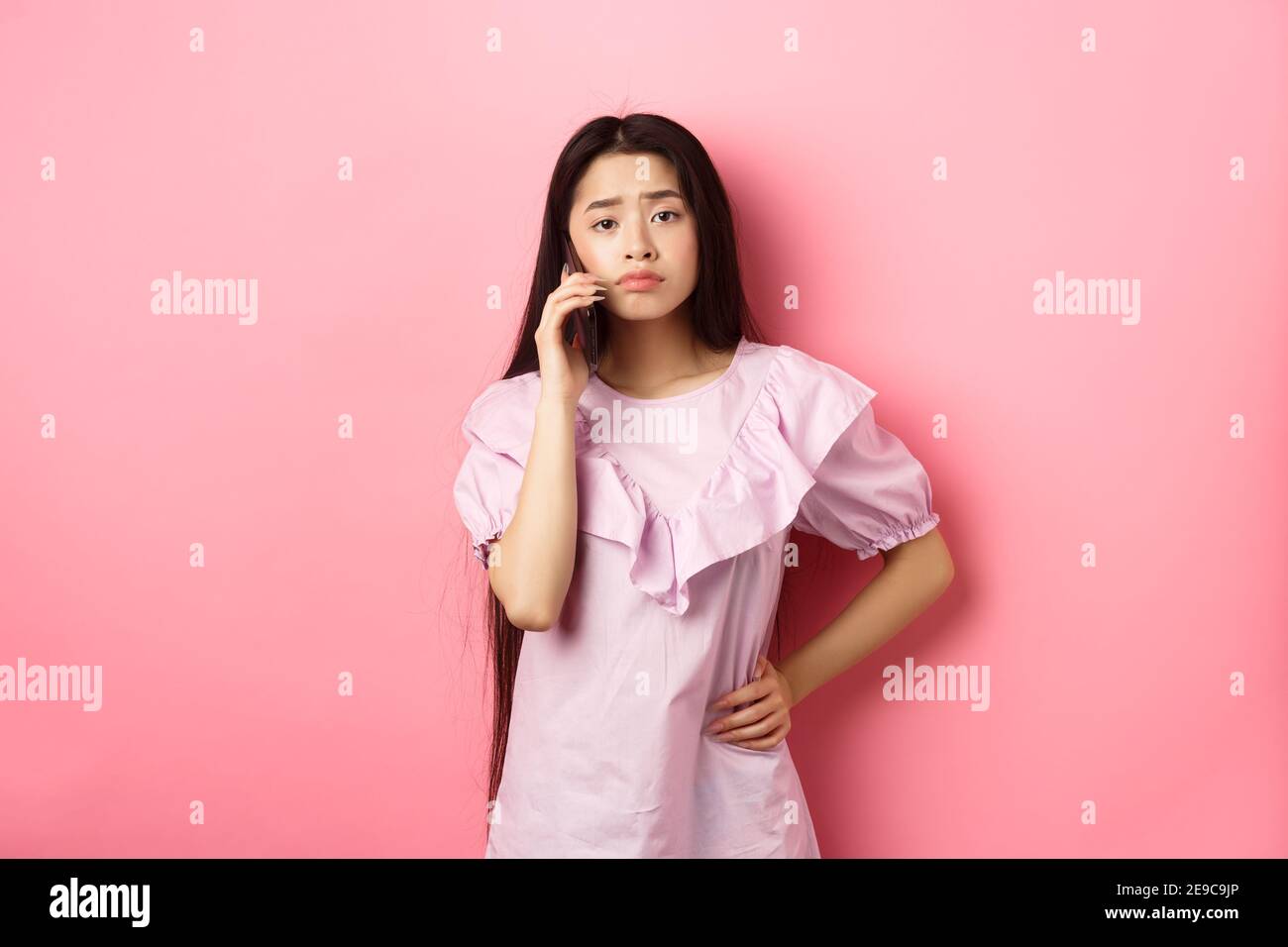 Sad asian girl calling someone, holding phone and talking, standing ...