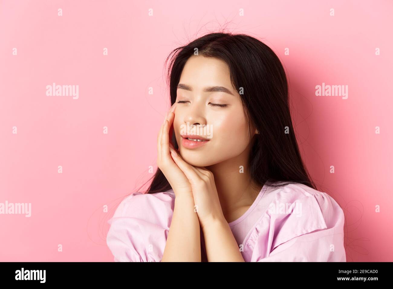 Tender and romantic girl gently touching face, close eyes and smiling ...