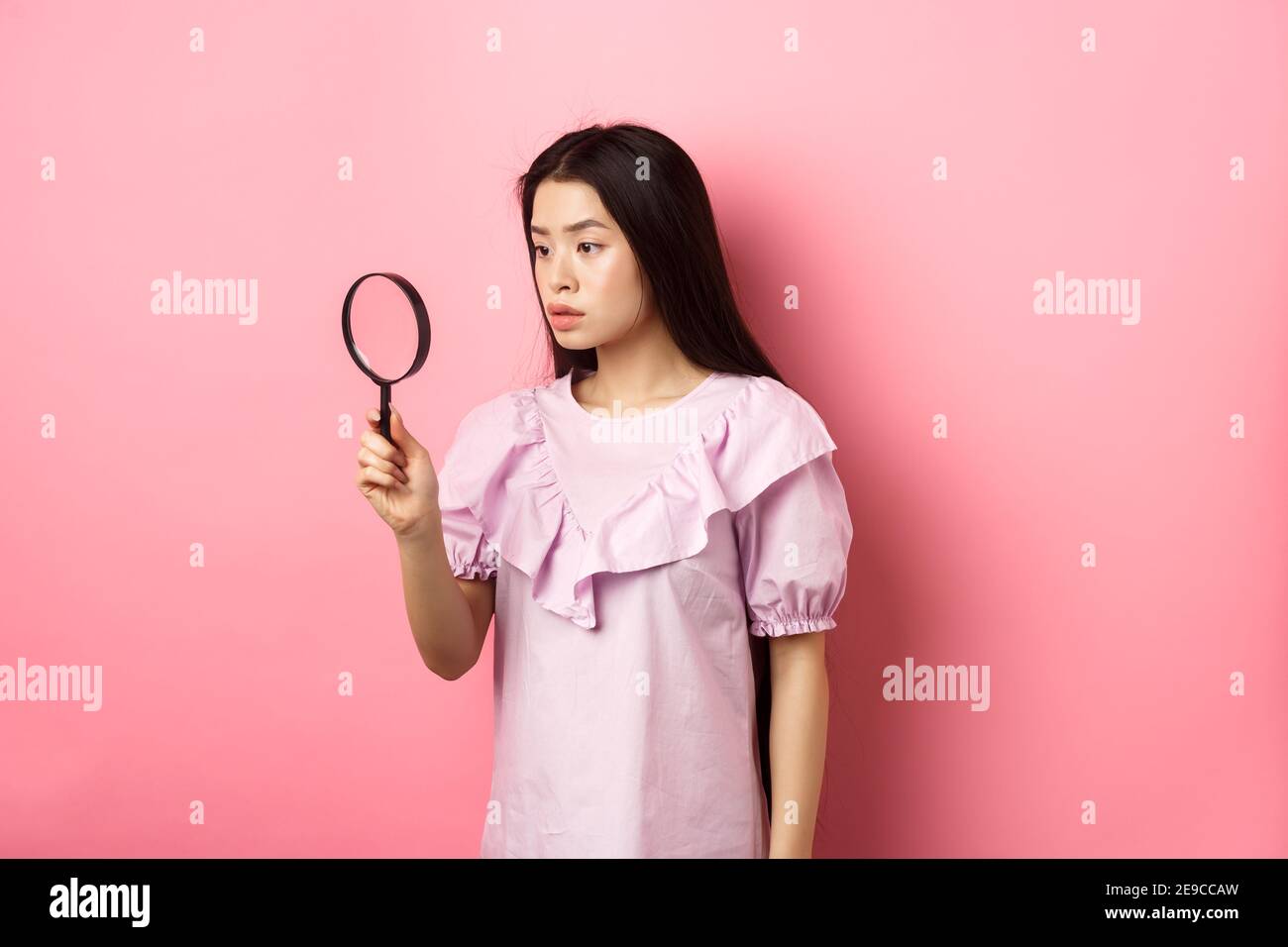 Serious girl investigating, looking through magnifying glass, searching ...