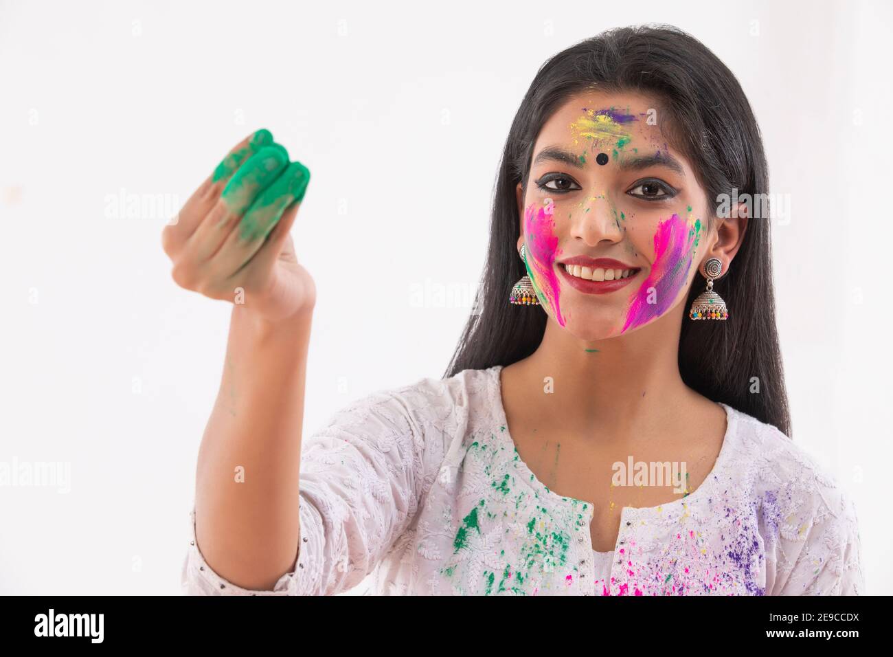 A HAPPY YOUNG WOMAN WITH GULAL IN HAND WHILE CELEBRATING HOLI Stock ...