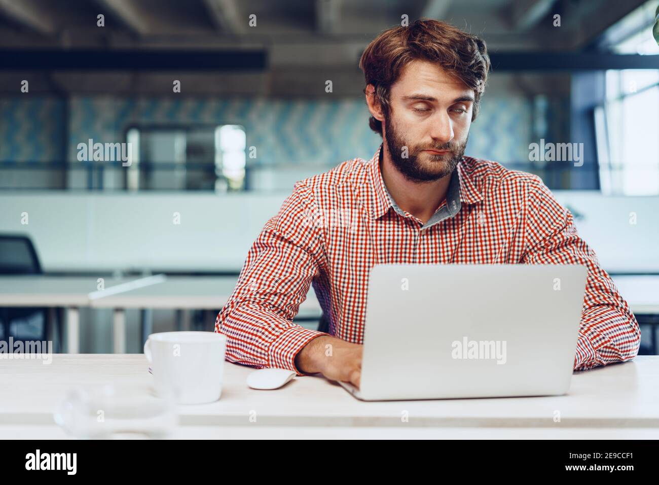 Tired businessman working on his computer in open space office Stock ...