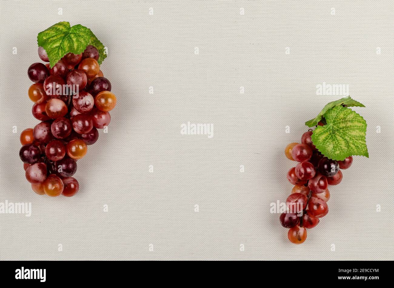 Two clusters of red grapes on a light brown background. Food ...