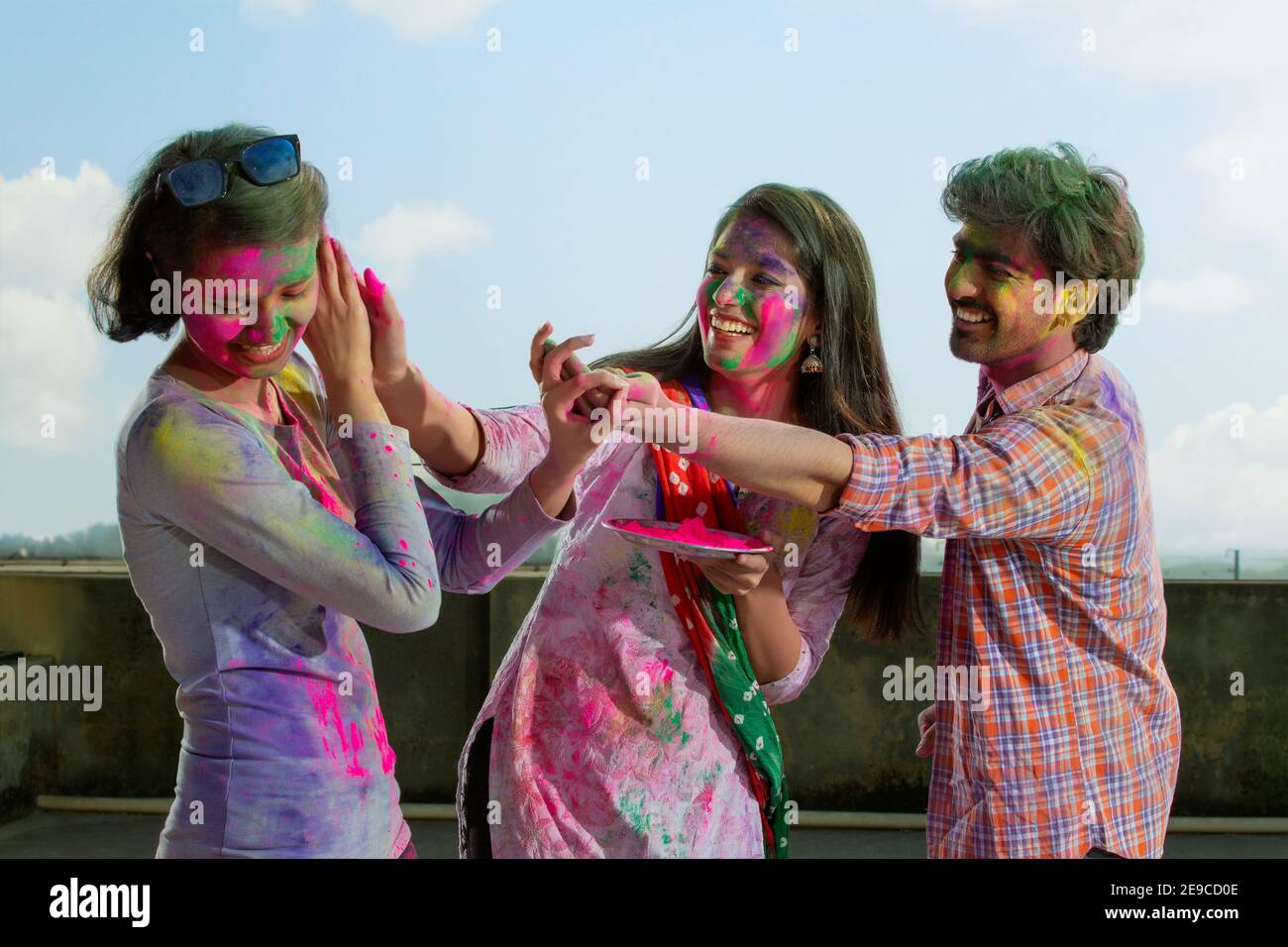 TWO FRIENDS HAPPILY PUTTING COLOURS ON ANOTHER FRIEND Stock Photo - Alamy