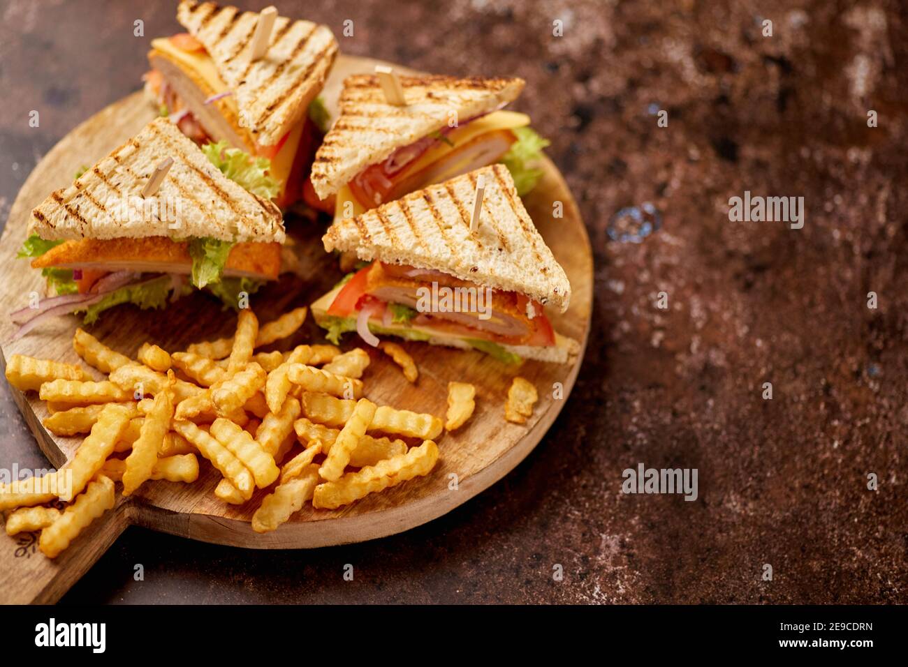 Chicken and cheese club sandwiches served on a wooden board with french ...
