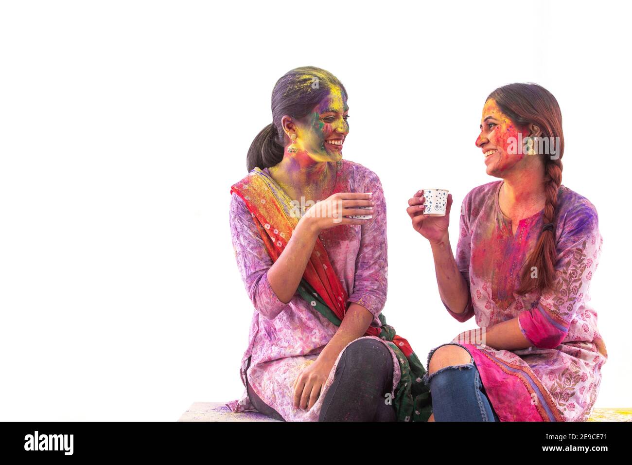 TWO YOUNG WOMEN HAPPILY SITTING AND DRINKING TEA AFTER PLAYING HOLI ...