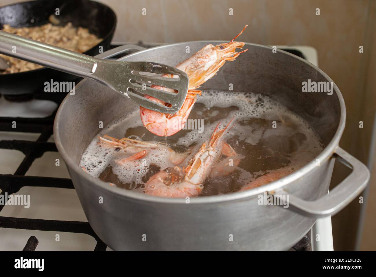 The prawns are boiled in a saucepan on a gas stove. Natural light from ...