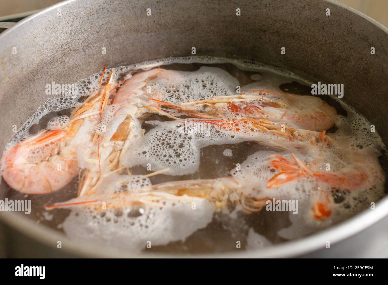 The prawns are boiled in a saucepan on a gas stove. Natural light from ...