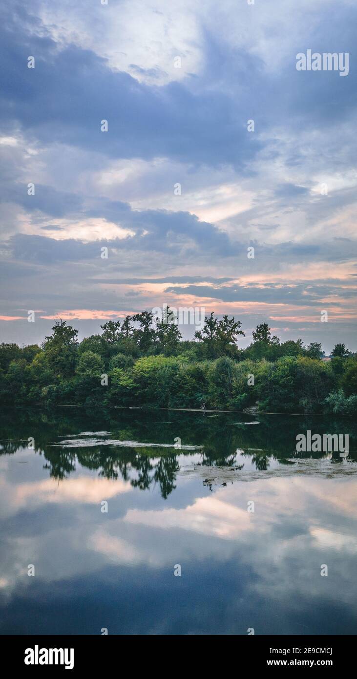 Vertical shot of trees reflecting in the lake at scenic sunset Stock ...