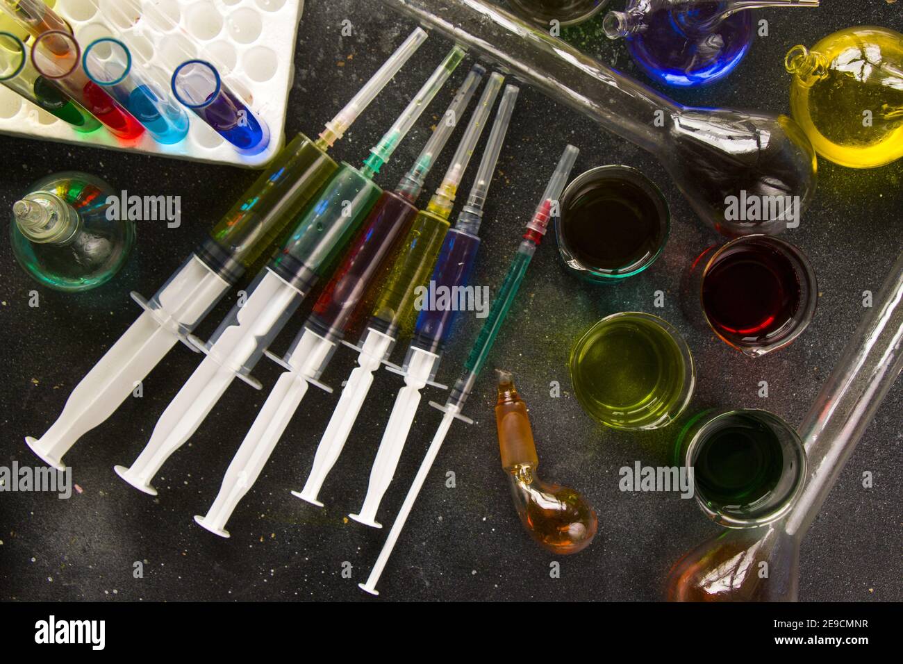 Top view of syringe needles, tubes, and beakers with colorful chemical ...